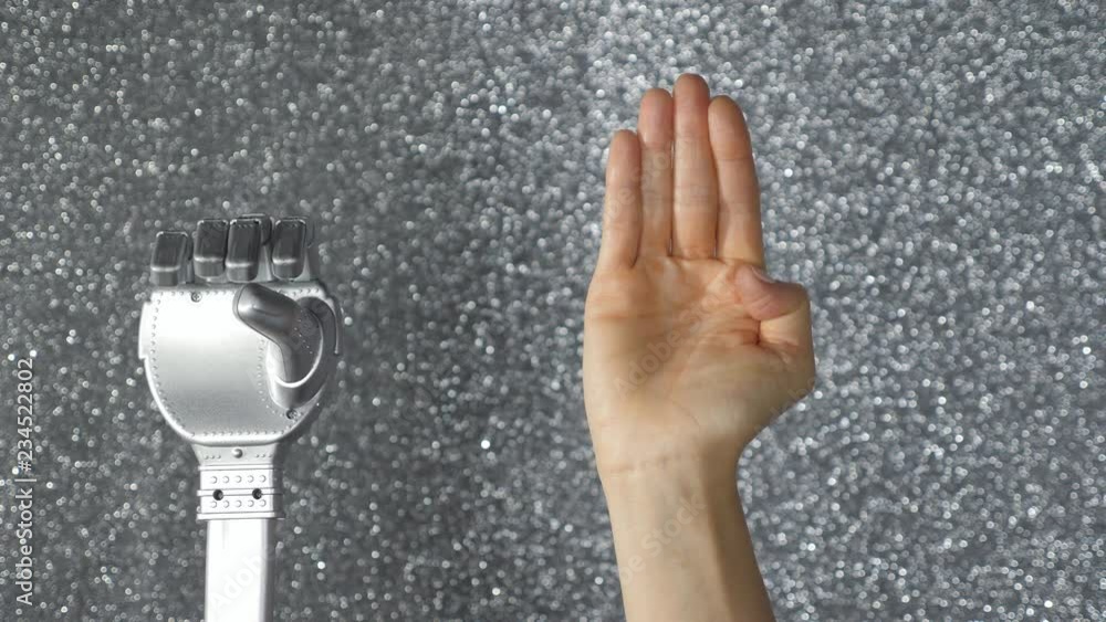 Silver robotic toy hand mimics clenching gesture of human female hand ...