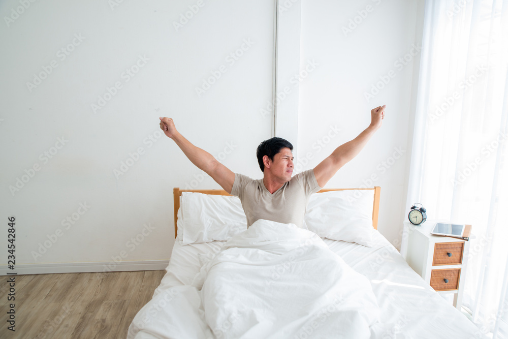 Asian handsome man waking up in the early morning. Outstretched arms ...