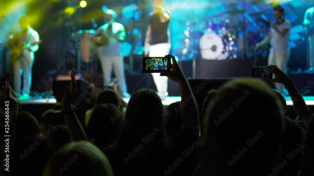group of people at concert, taking photographs of stage, using ...