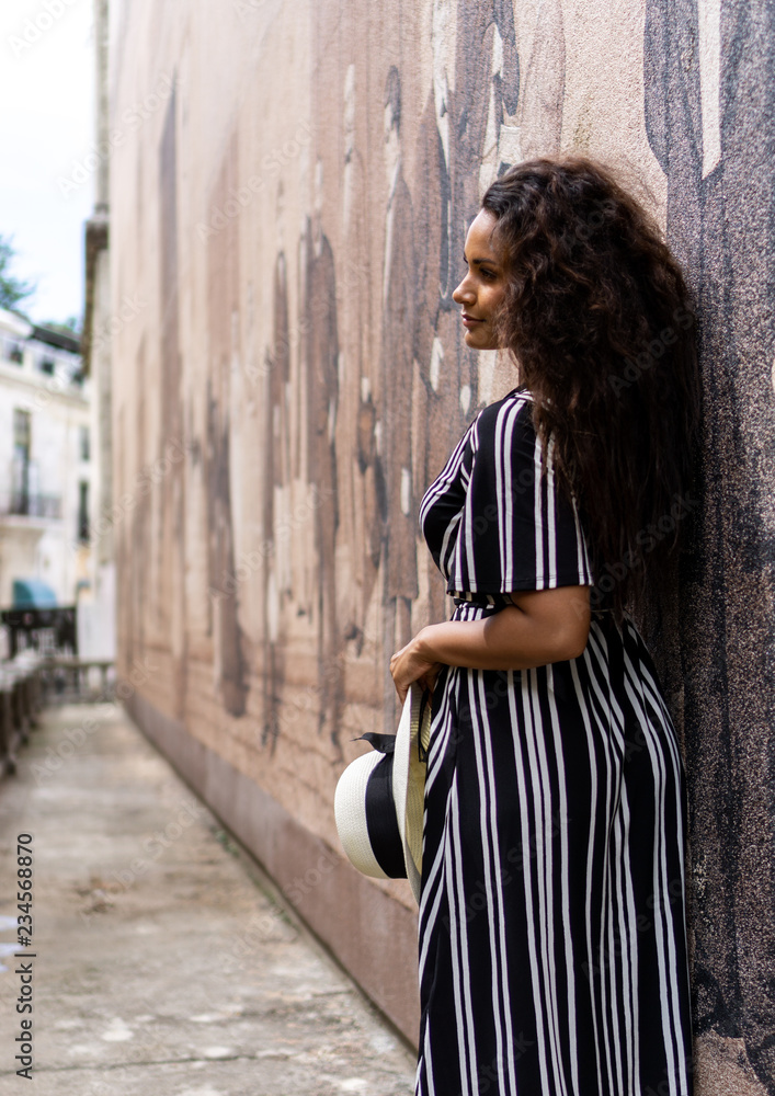 Young lady with curly hair and a black and white dress posing in front ...