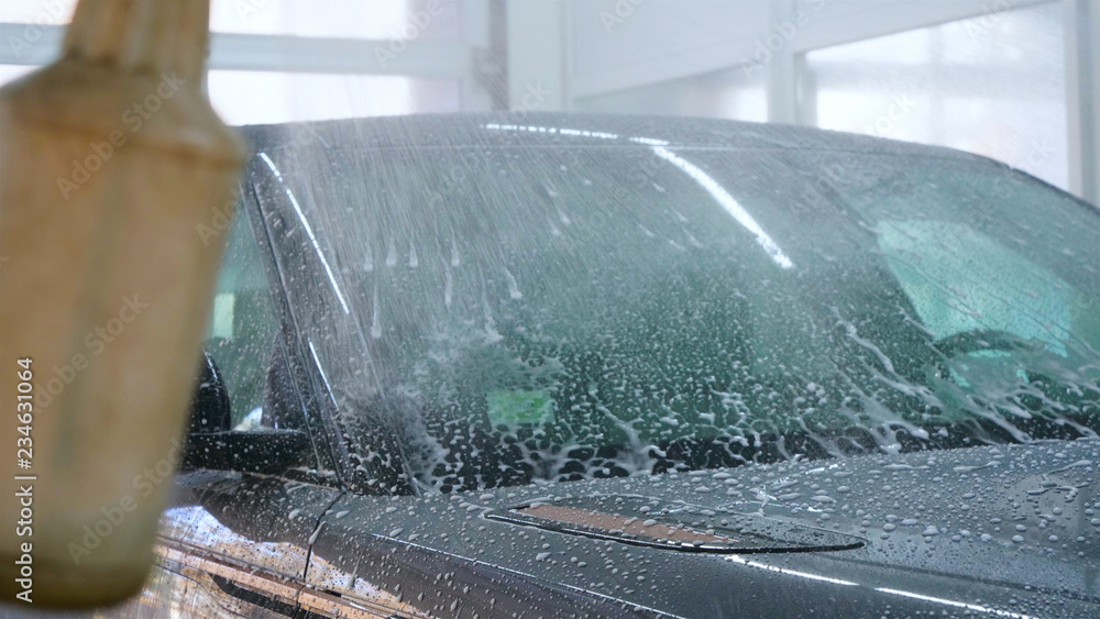 At the car wash, after washing, water drops and wax flow down the ...