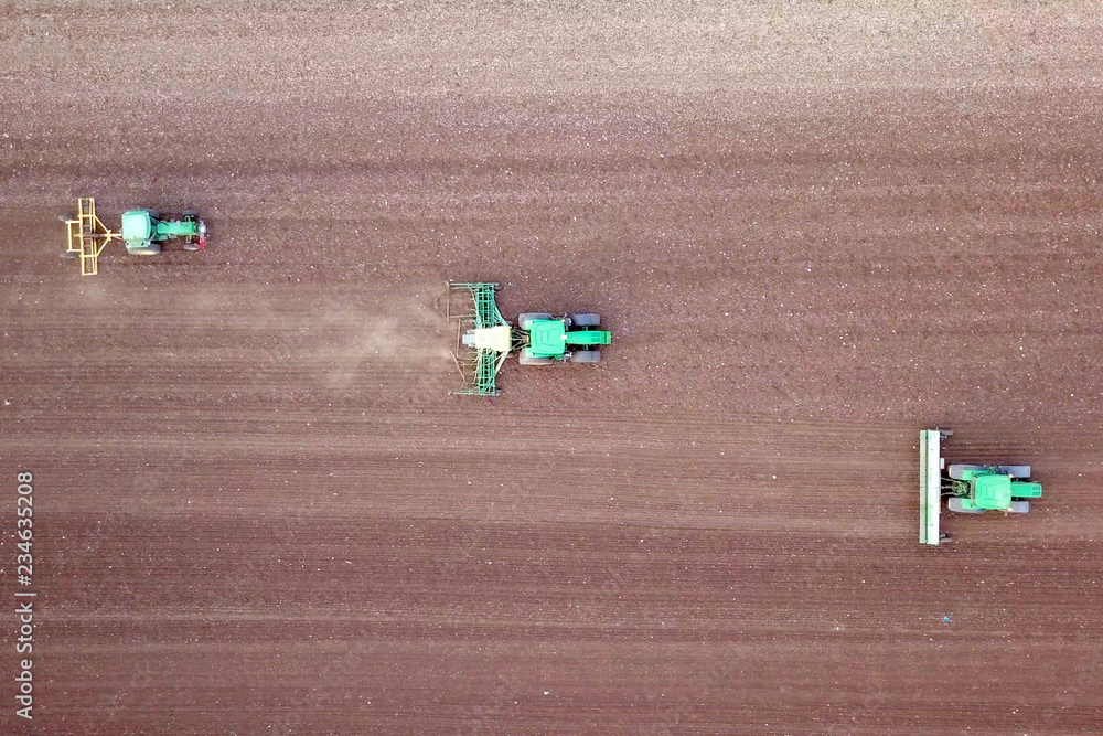 Three Tractors cultivating and seeding a dry field - Top down aerial ...