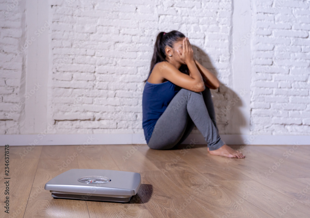 Sad woman or teenager girl afraid of weight looking at scale in ...