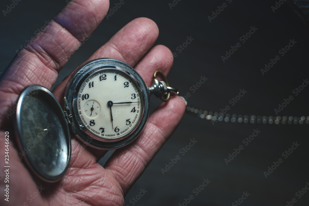 old man holds in his hand a retro pocket watch on a chain, the concept ...