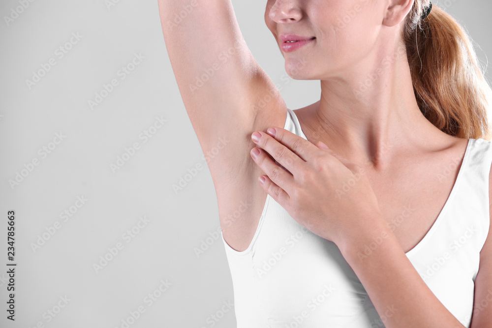 Young woman showing armpit on grey background, space for text. Using ...