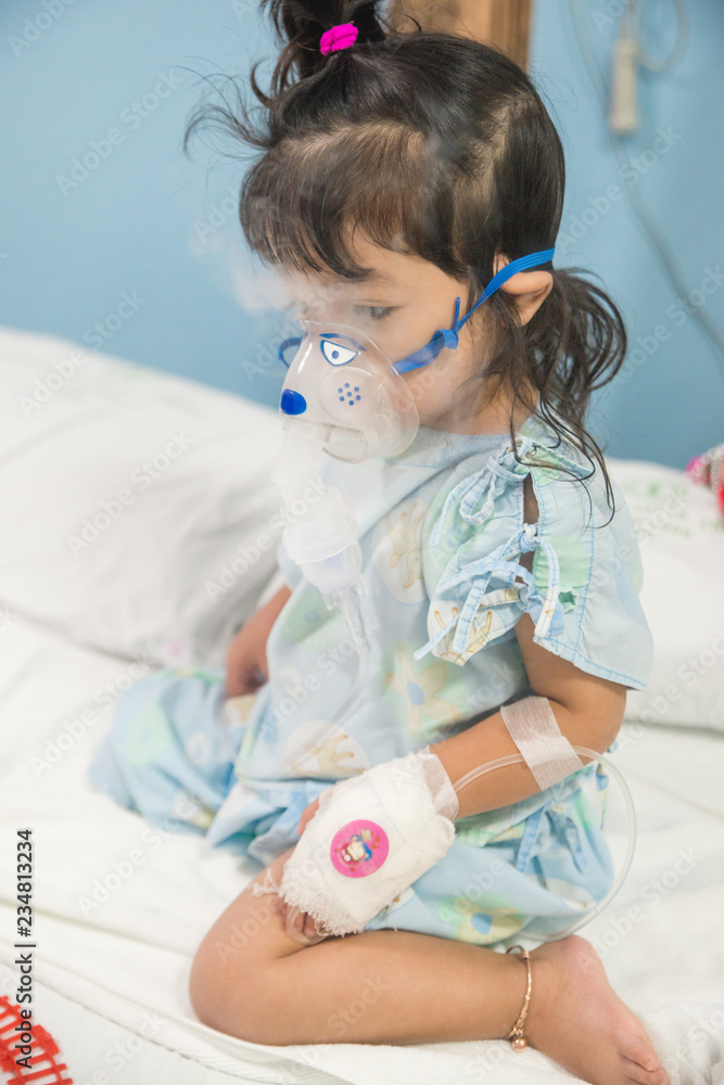 Asian little girl making inhalation with nebulizer at hospital. child ...