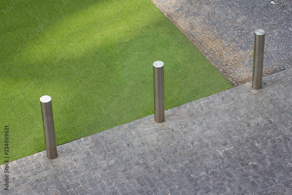 stainless steel bollards on floor between rock footpath and green grass ...