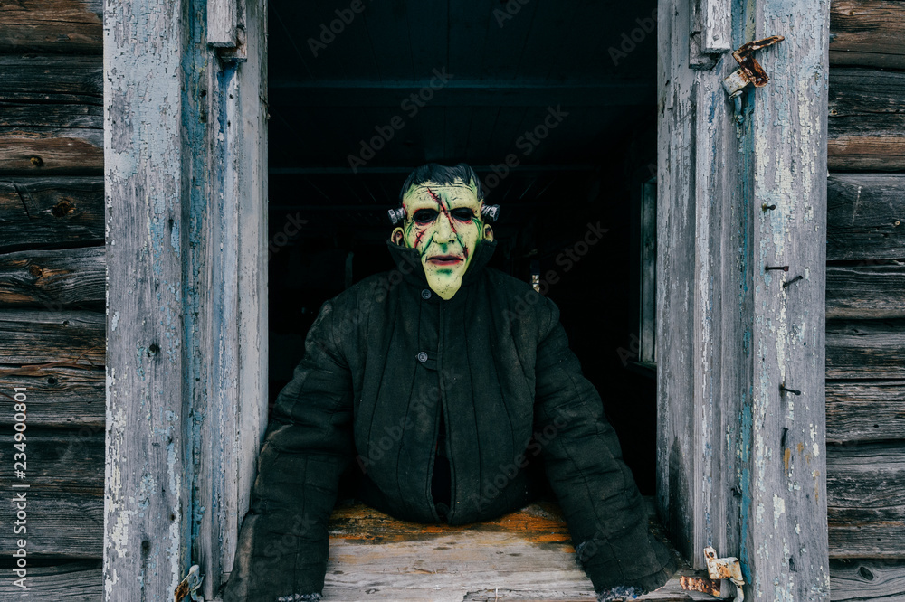 Unknown person with creepy horrible latex mask looking out from old ...
