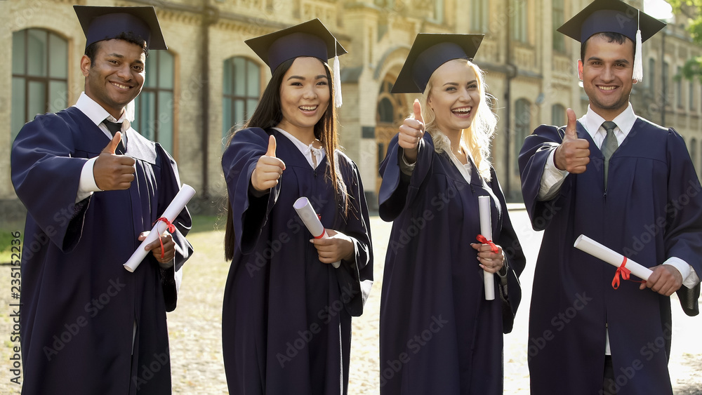 University graduates in academic regalia holding diplomas, showing ...