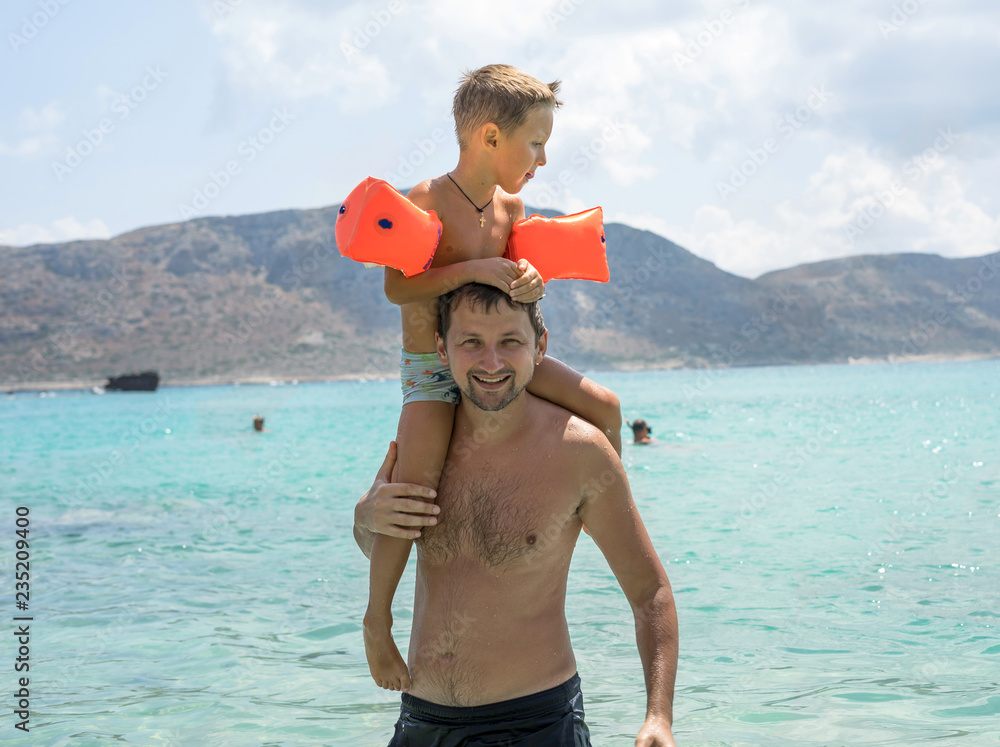 Foto de Happy father giving shoulder ride on his shoulders at the beach ...