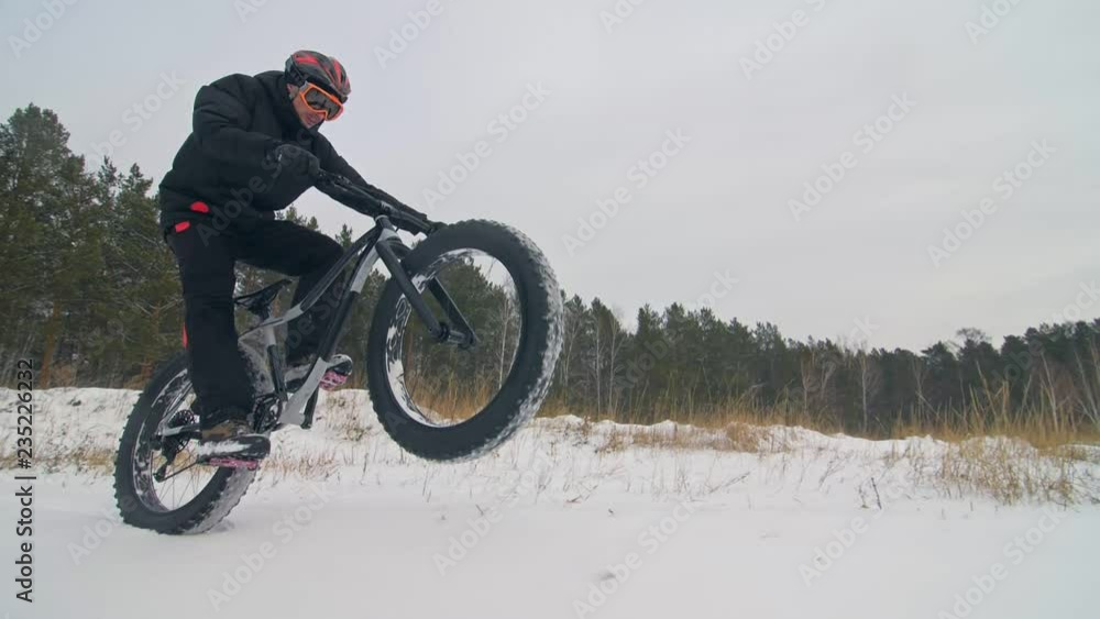 Professional extreme sportsman biker riding fat bike in outdoors ...