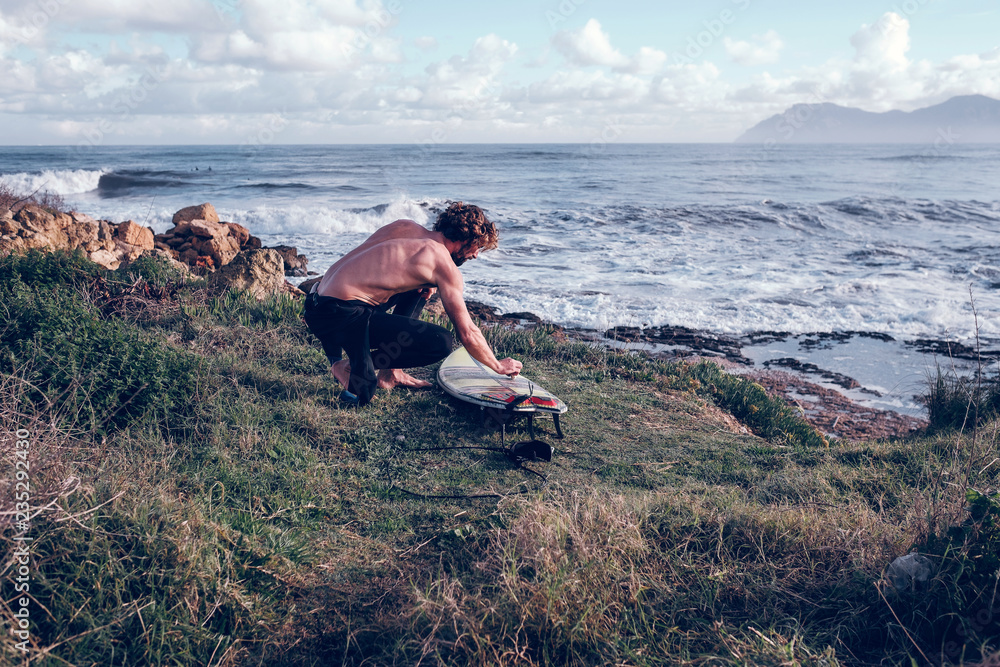 Shirtless young man cleaning surfboard Stock Photo | Adobe Stock