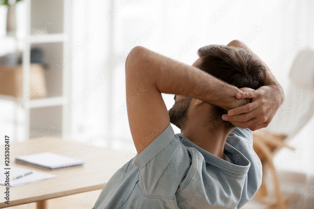 Back view of tired man lean back in chair relaxing working long at ...