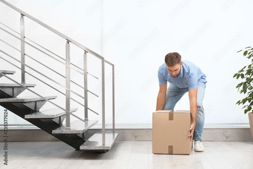 Young man lifting carton box indoors. Posture concept Stock Photo ...