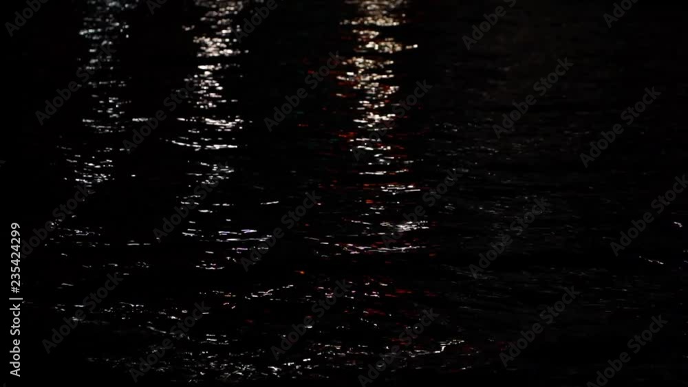Streaks of lights on rippling sea water surface at night time. Dark ...
