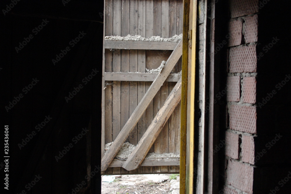 An vies at a pars of wooden gates through an open door from inside of ...