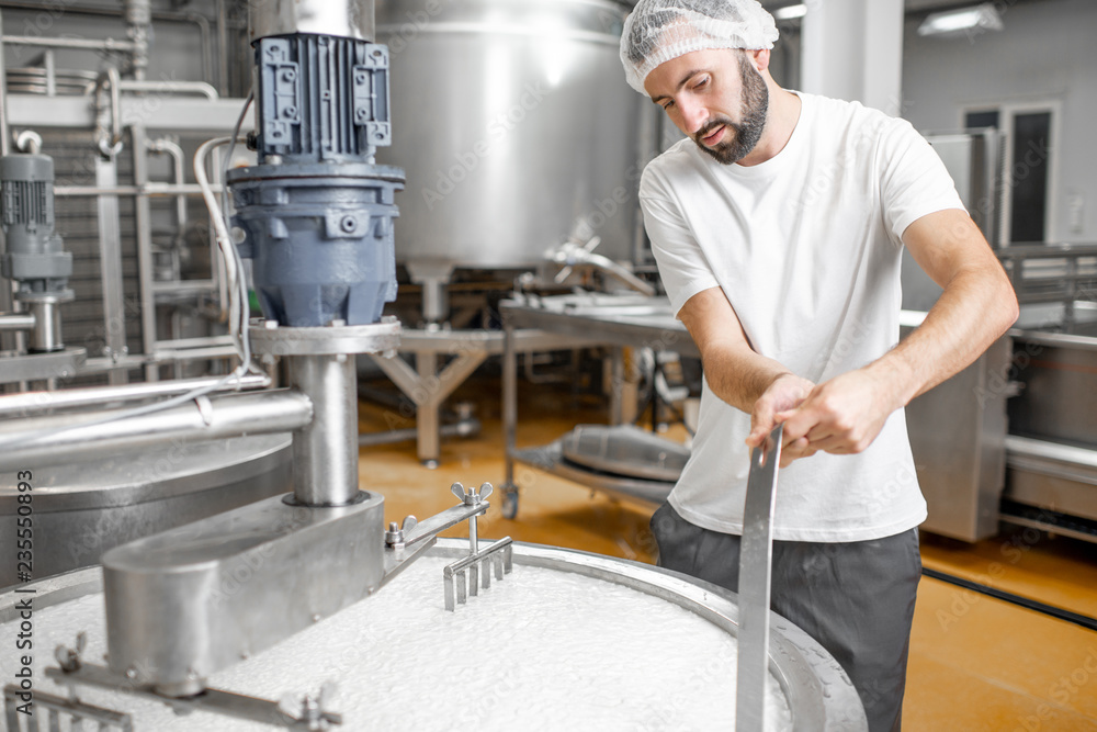 Man mixing milk in the stainless tank during the fermentation process ...