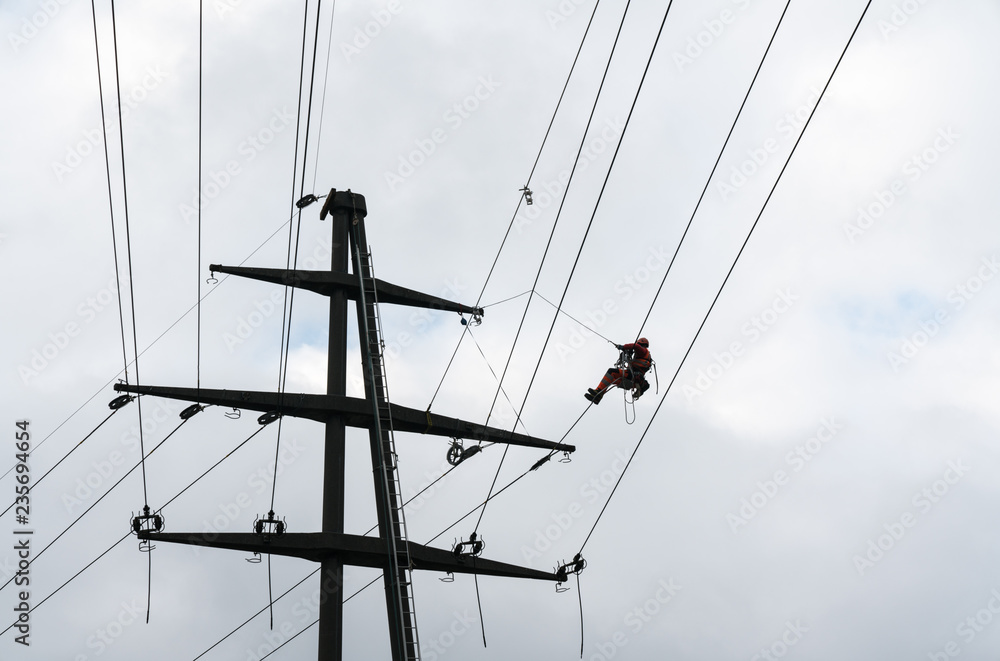 working professional men on high voltage power lines high up on lattice ...