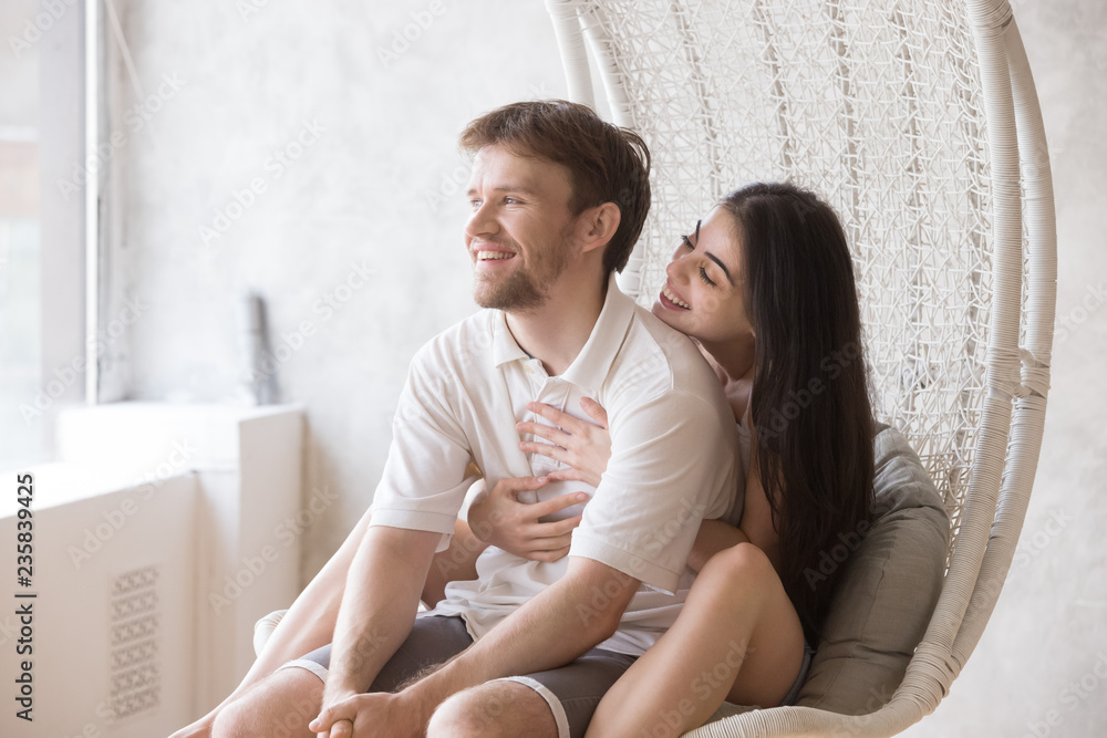 Happy loving couple sitting together in lounge hanging chair ...