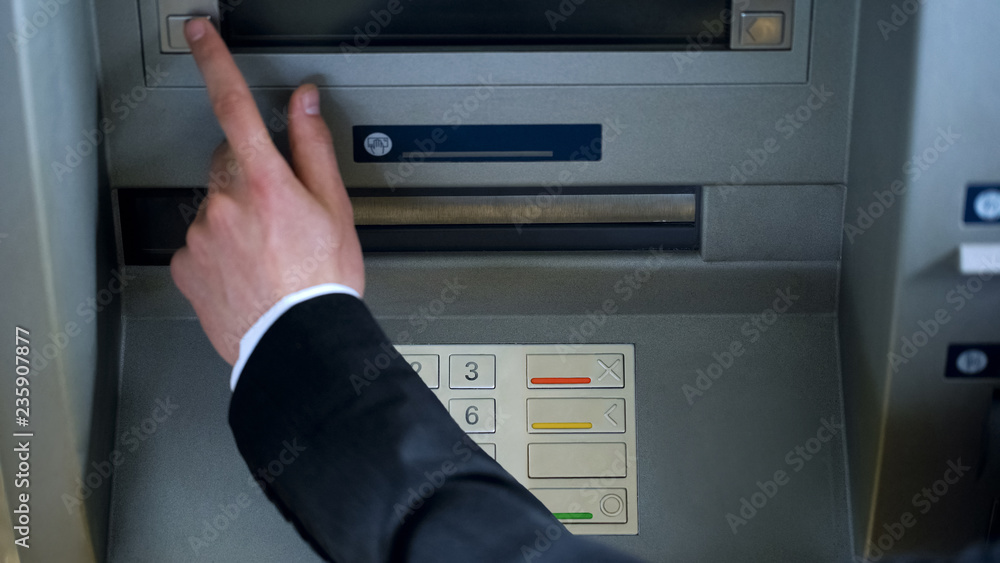 Mans hand pressing button on display screen of ATM machine, bank ...