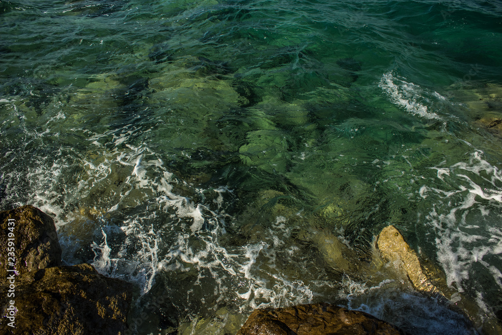 sea shore line and vivid blue water surface with waves breaks on rocks ...