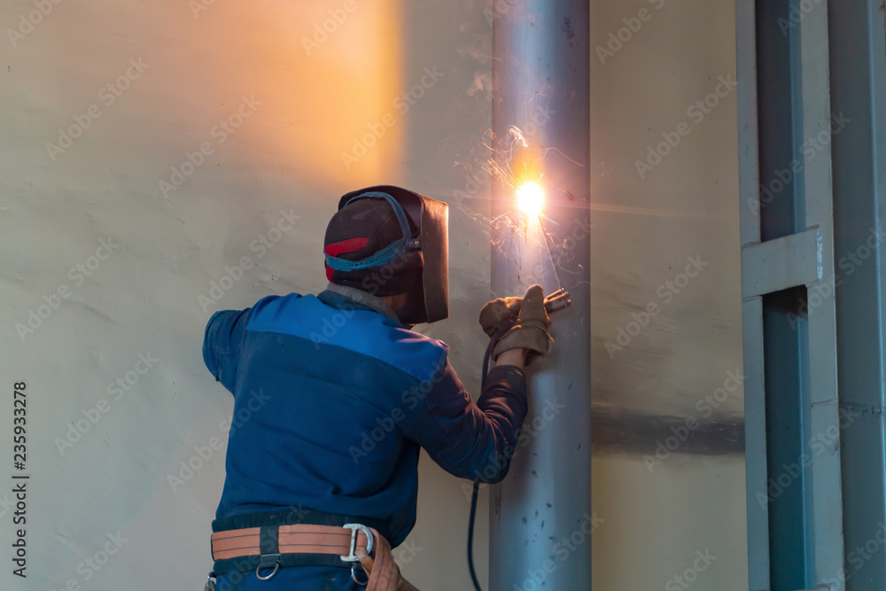 A worker, a welder in working clothes, a welding mask and leather ...