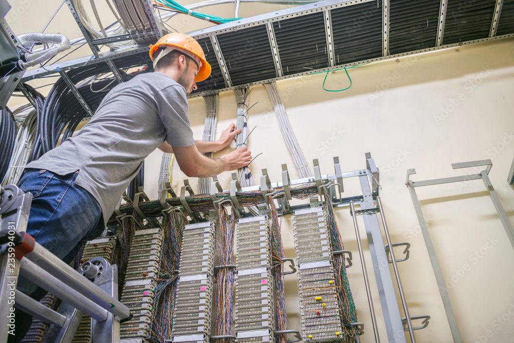 The engineer standing on the stairs works with the switching equipment ...