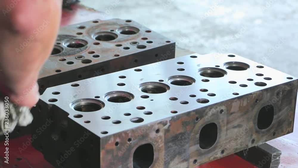 Worker cleans the cylinder head and block after grinding on the machine ...