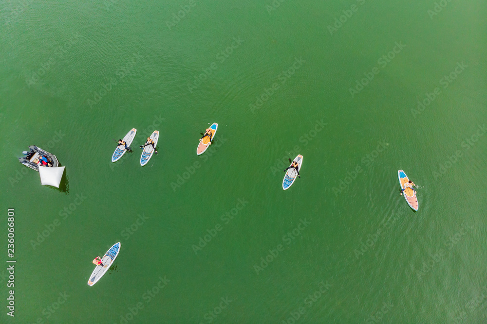 Strong men floating on a SUP boards in a beautiful bay on a sunny day ...