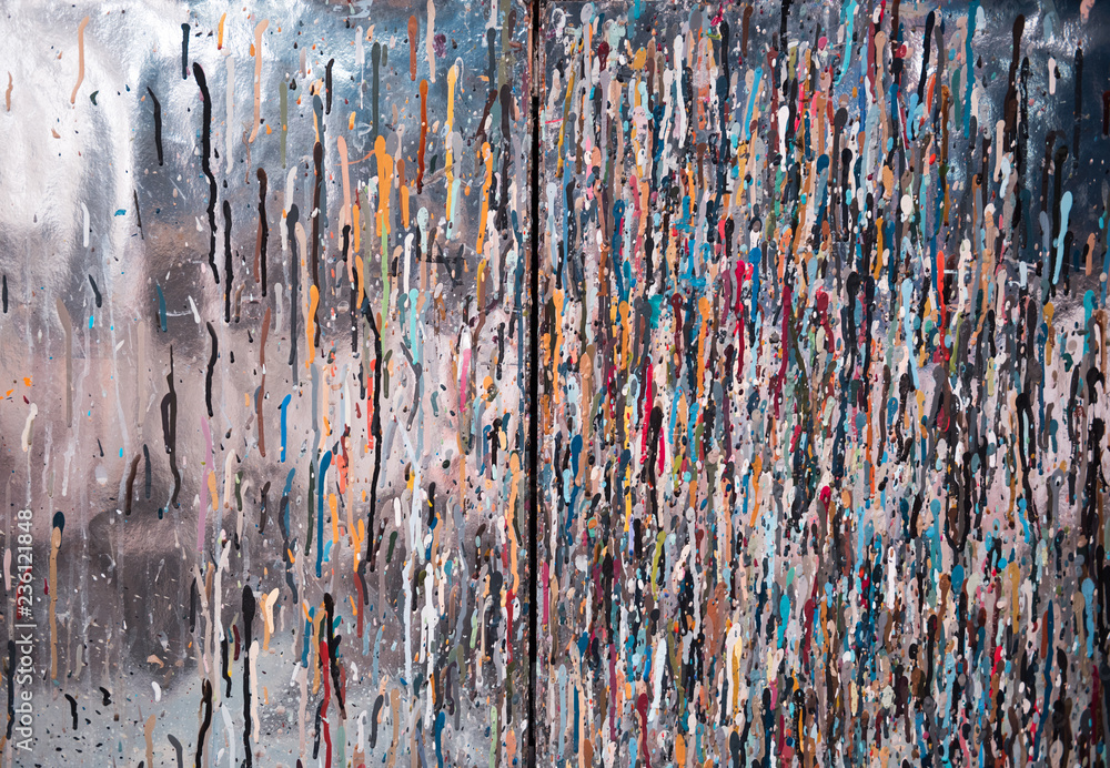 Artistic colourful ink and paint drips on a silver metallic textured ...
