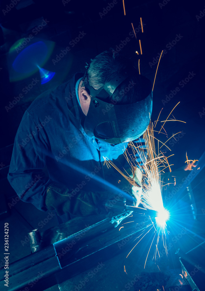 A vibrant action shot of a skilled working metal welder in action ...