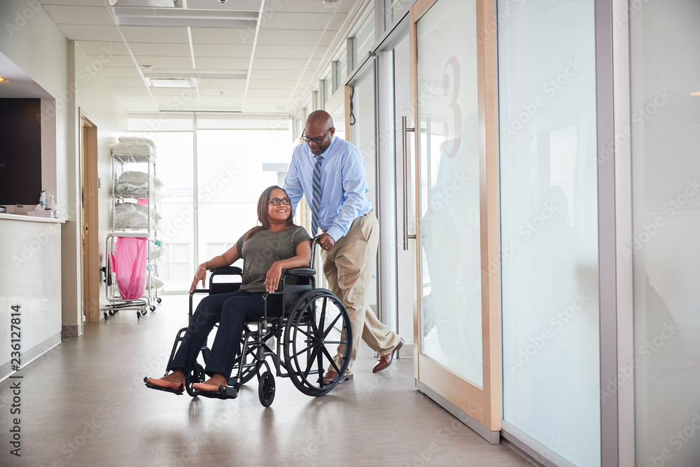 Man pushing woman in a wheelchair Stock Photo | Adobe Stock