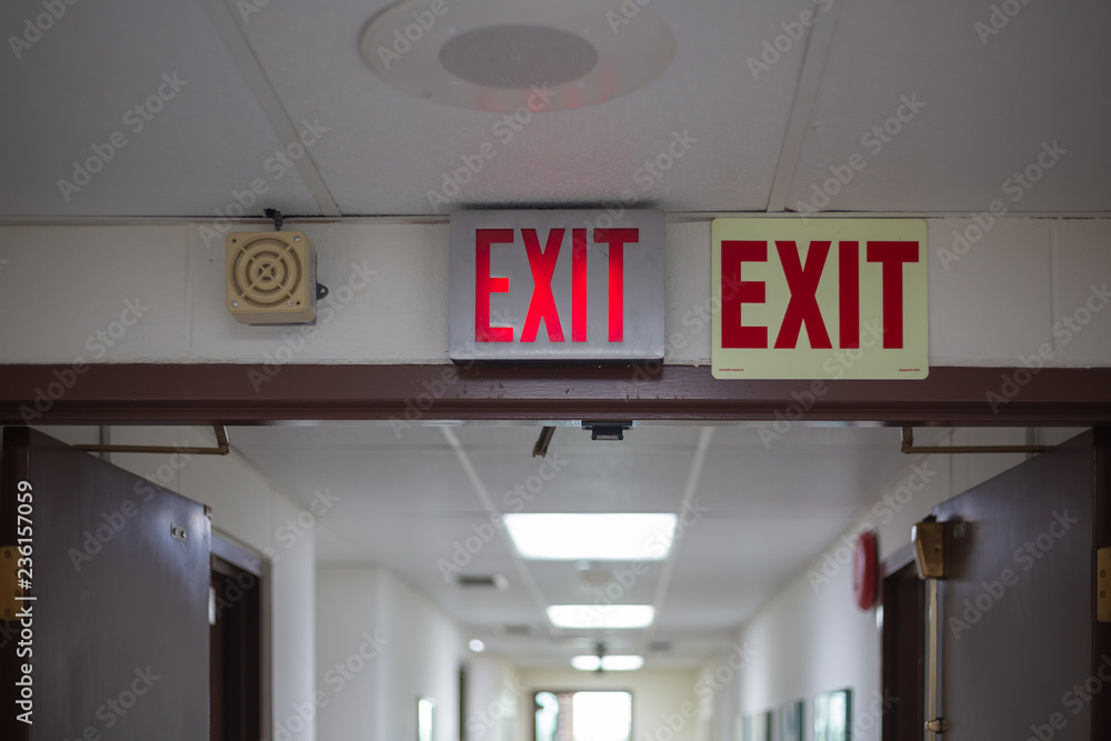 red emergency exit sign in the dark room. illuminated office exit sign ...