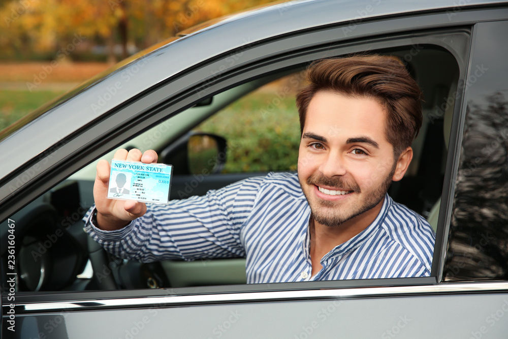 Young man holding driving license in car Stock Photo | Adobe Stock