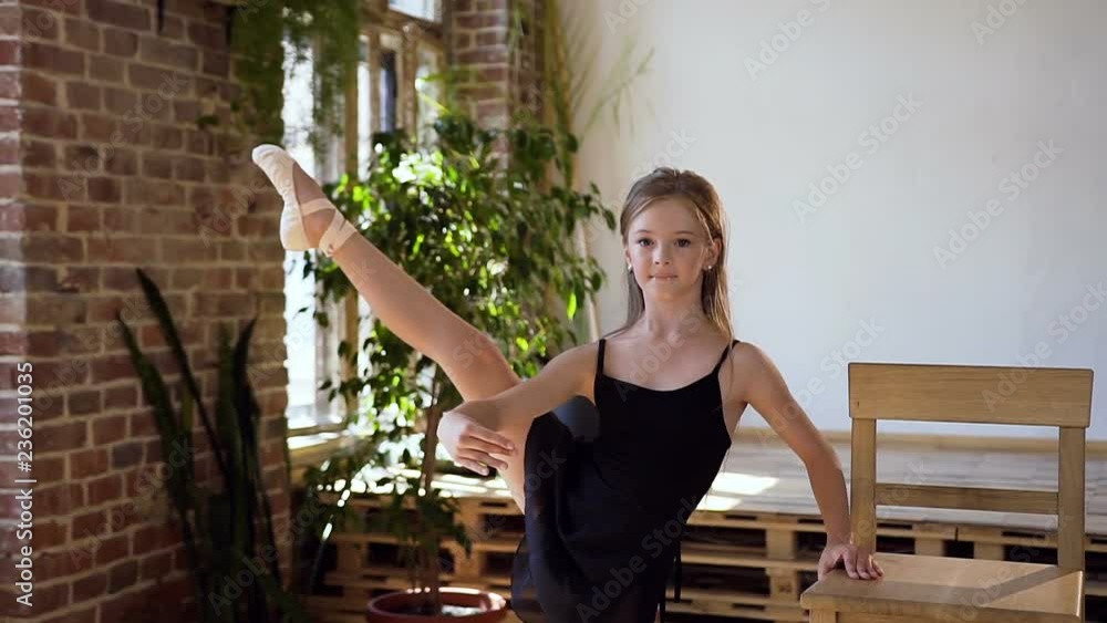 Charming girl in black tutu performs element of classical ballet ...