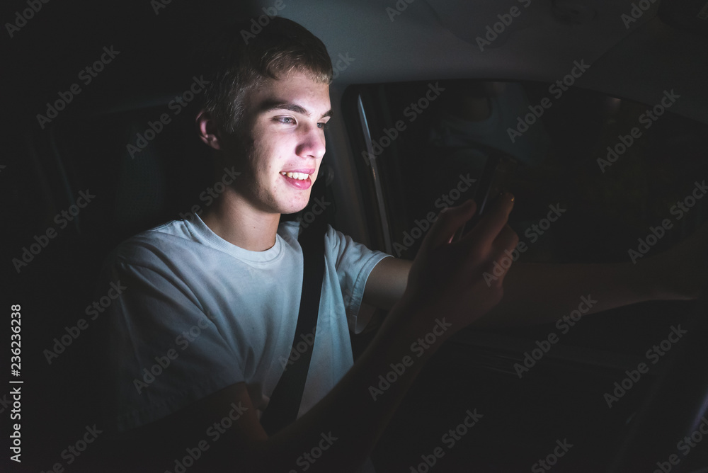 Distracted teenager driving a car with his cell phone in his hand. The ...