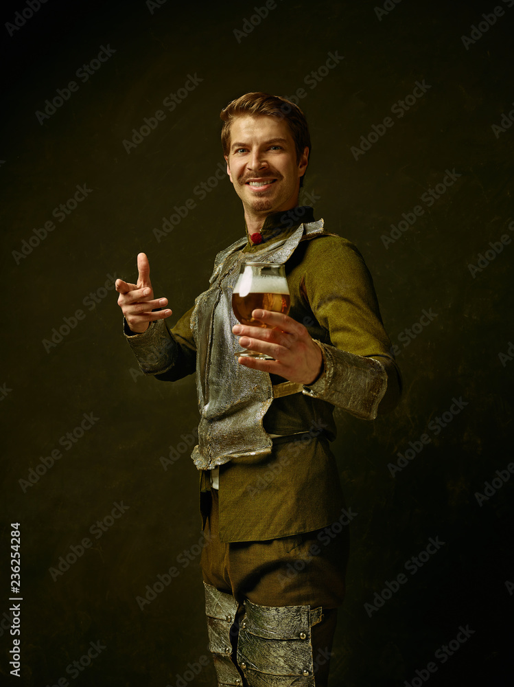 Medieval smiling happy knight with beer on dark studio background ...