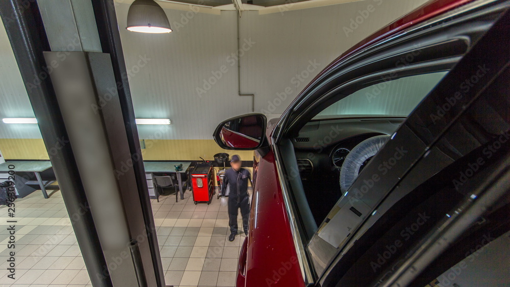 car mechanic drive red car from lift to wheels alignment camber check ...