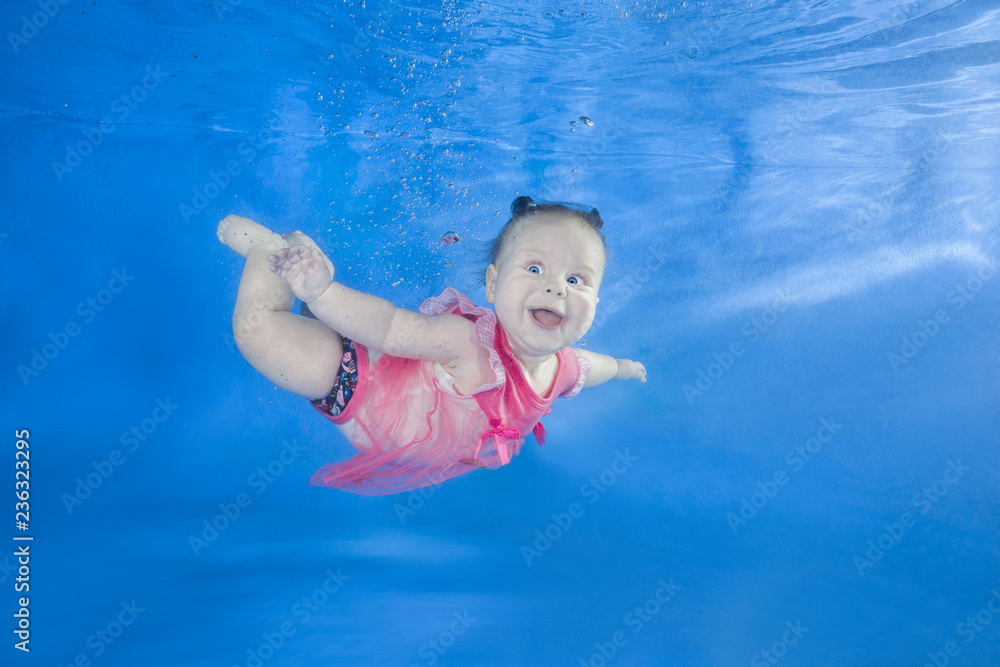 Little baby in pink dress swim underwater. Baby swimming underwater in ...
