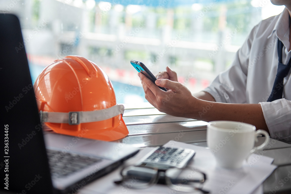 engineering working at construction office desk and holding mobile ...