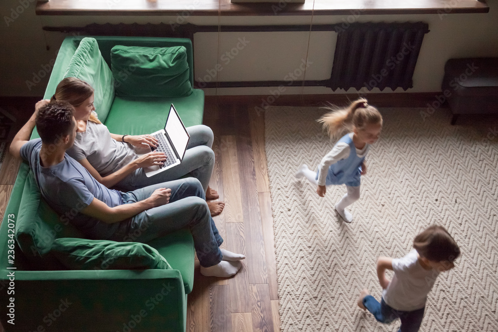 Foto de Little children playing catch-up while parents using laptop ...