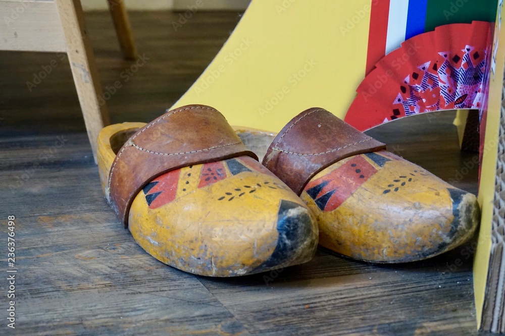 Old painted Dutch wooden clogs with a leather strap, on the floor of a ...