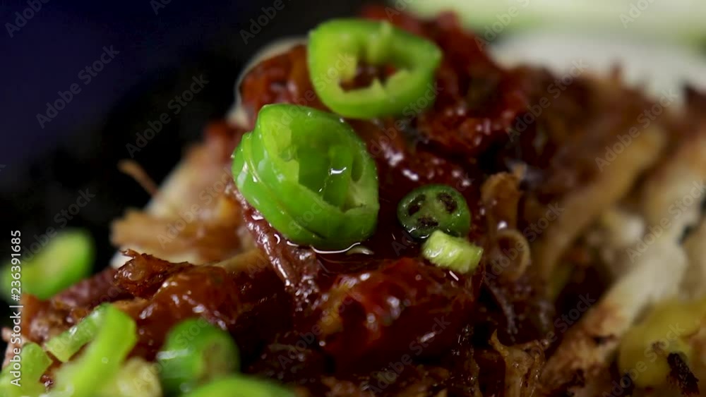 Extreme close up of green sliced chillies being topped on ripped ...