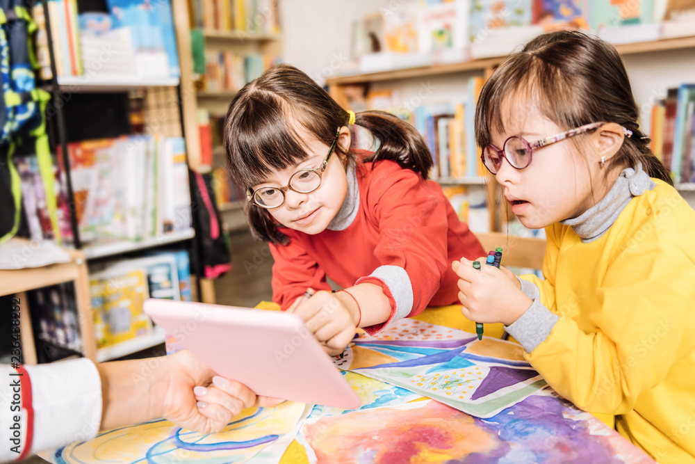 Dark-haired preschool girls with Down syndrome having drawing class ...