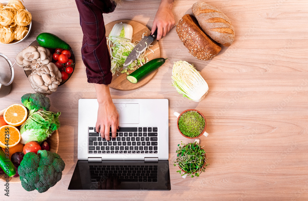 women in the kitchen searching for recipes on her laptop with food ...