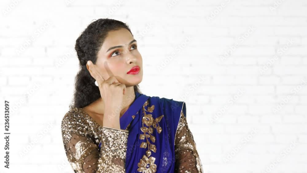 Beautiful young Indian woman thinking idea while standing and wearing ...