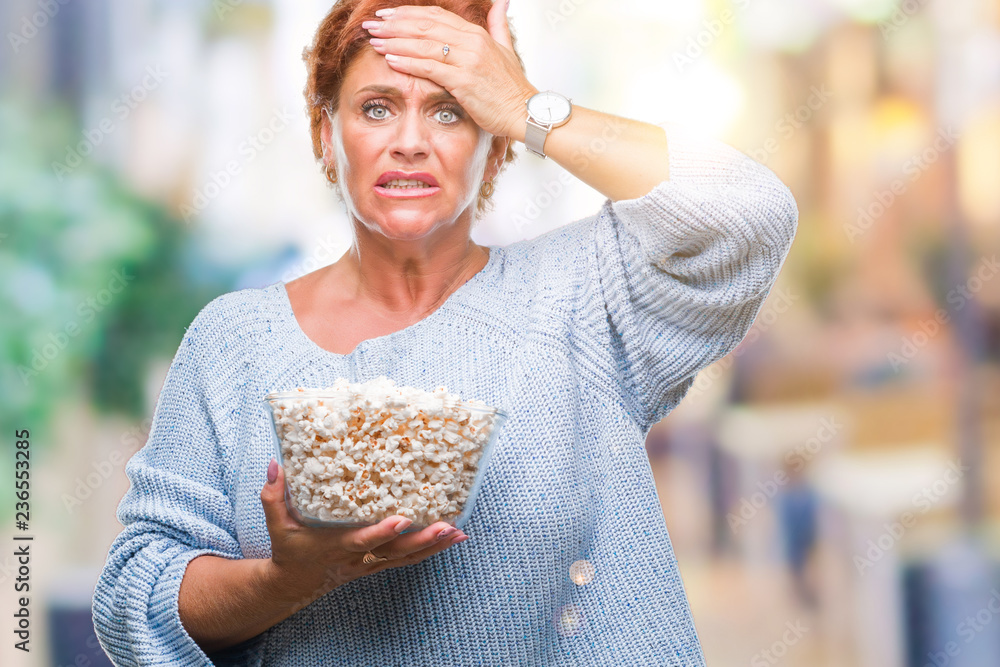 Atrractive senior caucasian redhead woman eating popcorn over isolated ...