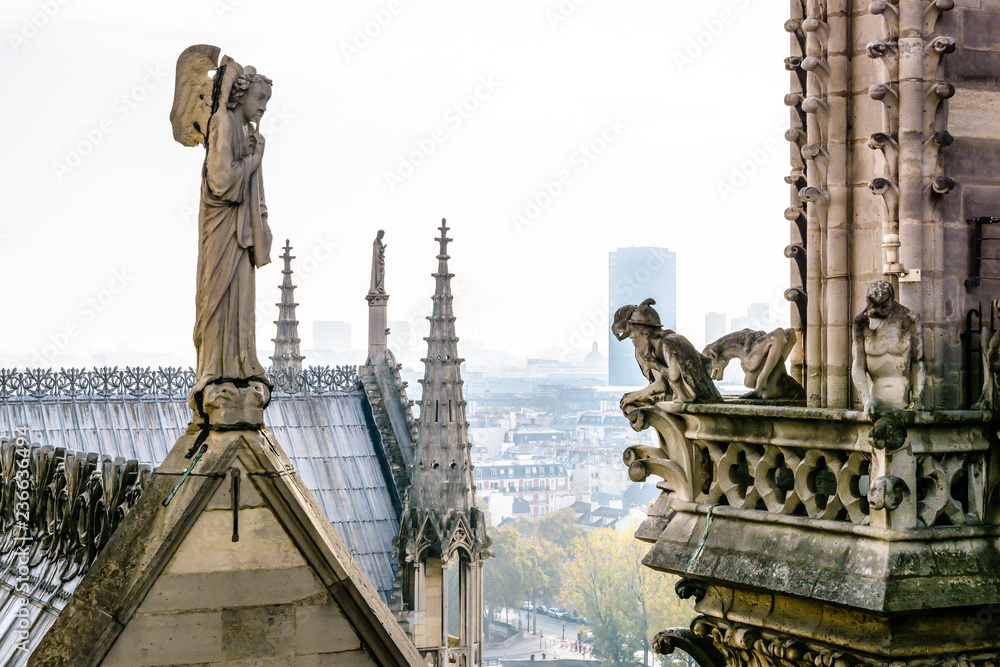 Stone statue of an angel with trumpet on the rooftop of Notre-Dame de ...