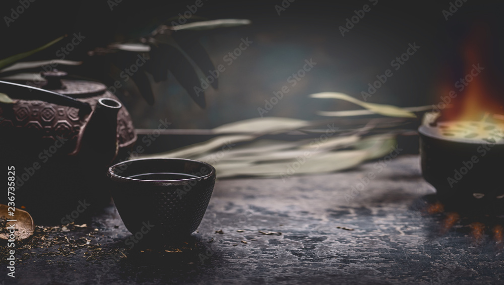 Dark tea background with black iron asian teapot and mug of hot tea on ...