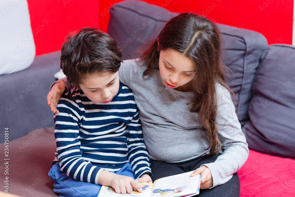 Cute little brother and sister reading story book at home Stock Photo ...